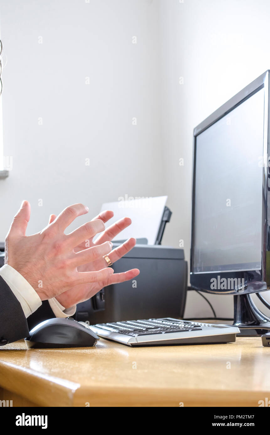 Businessman at office desk making angry gesture with hands towards ...