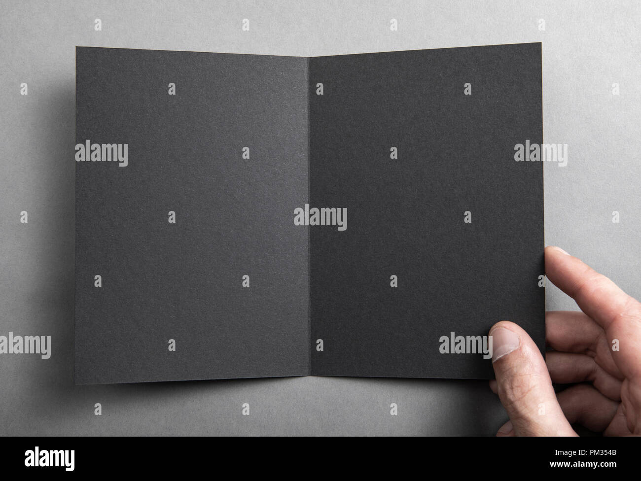 Mens hand holding empty black booklet on gray background. View from ...