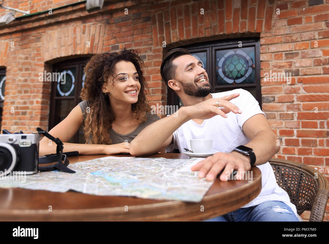 Young tourists drinking coffee at cafe and reading city map Stock Photo ...