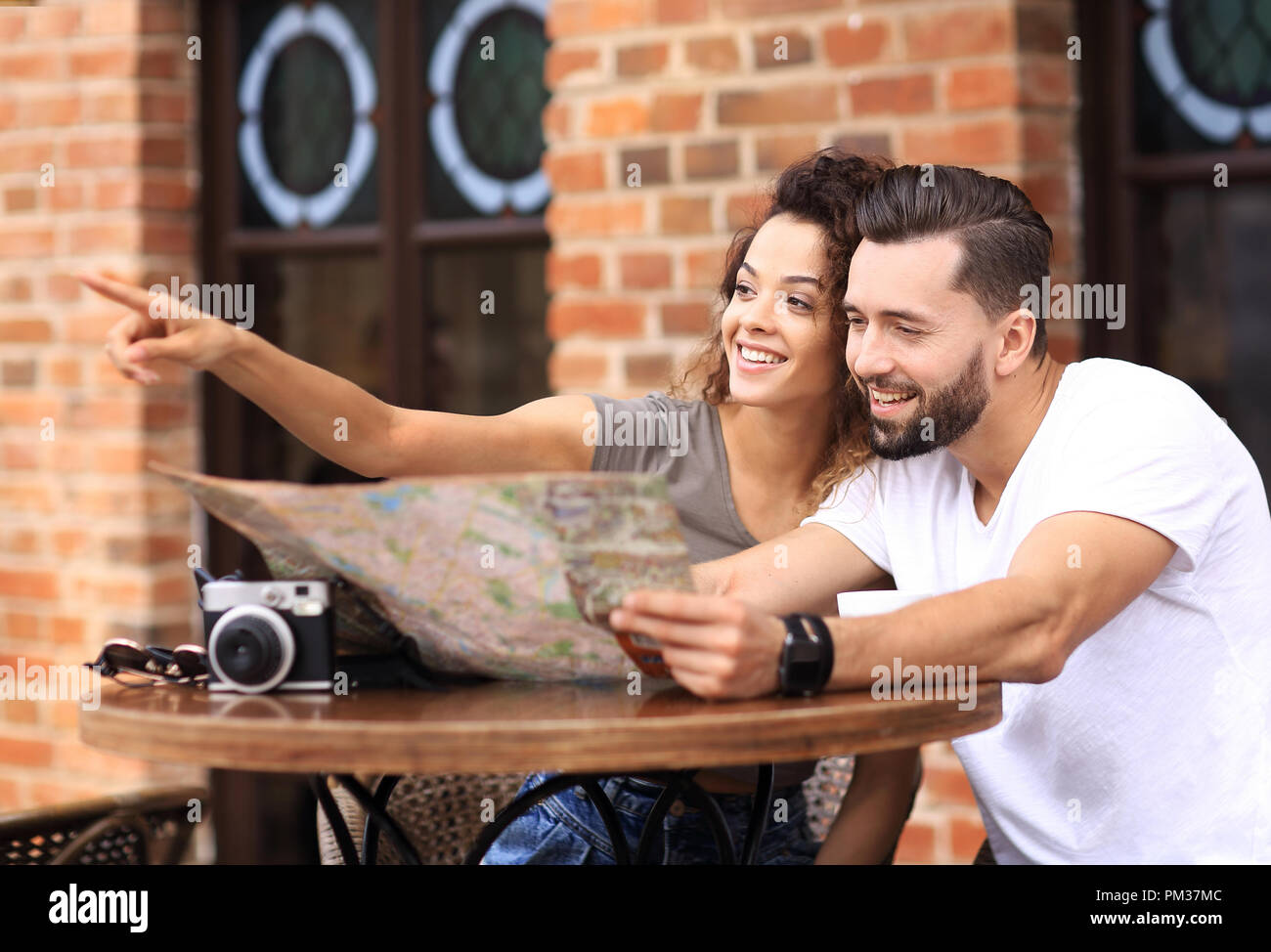 Young tourists having coffee at cafe and reading map Stock Photo - Alamy