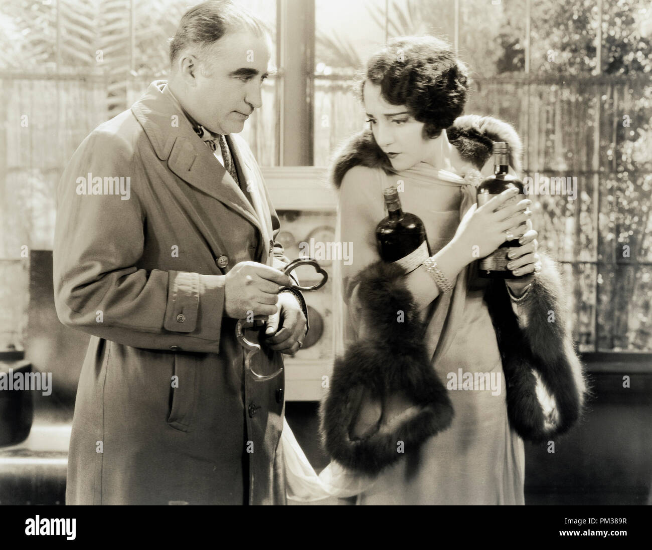 Silent film scene still. A lady clutching two bottles of liqour while a ...