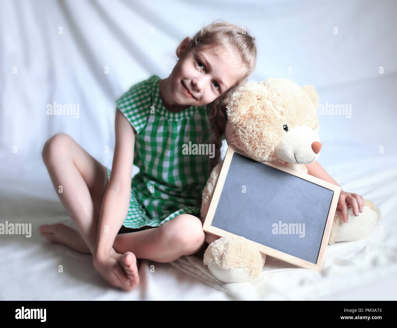 pretty little girl holds a stuffed toy with a greeting card for Stock ...