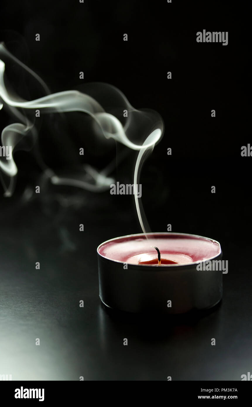A red candle on a black table is smoking after it is extinguished Stock ...