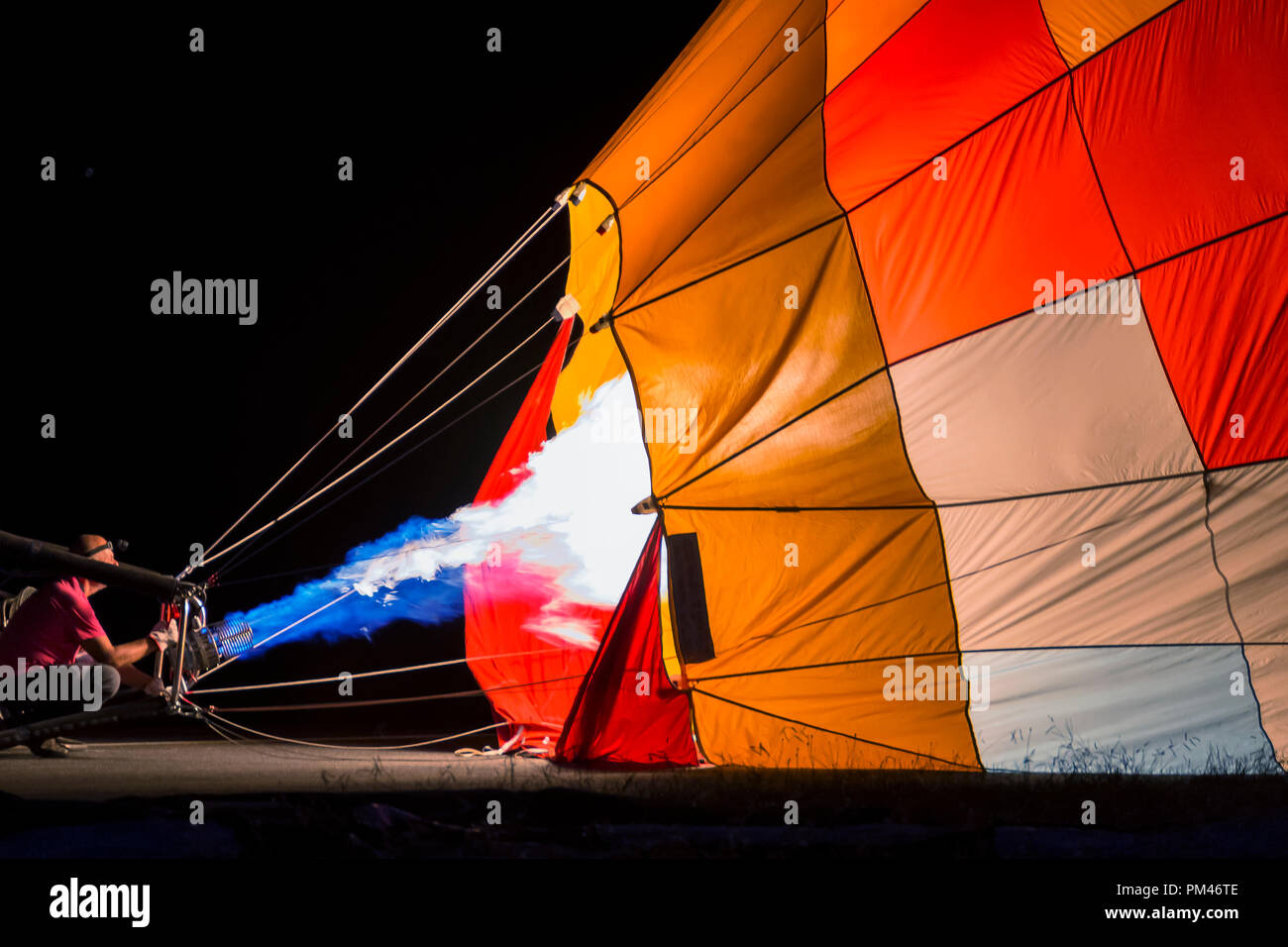 Inflating a very colorful balloon with the flame lit at night Stock ...