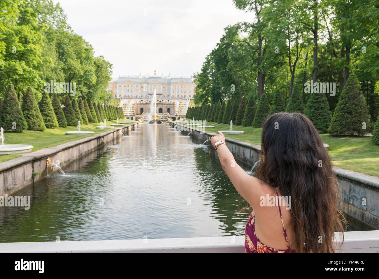Wide angle picture of brunette woman pointing to Peterhof Palace ...