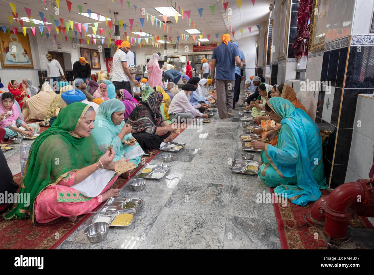 Women and some men eating in a Sikh temple langar where a free ...
