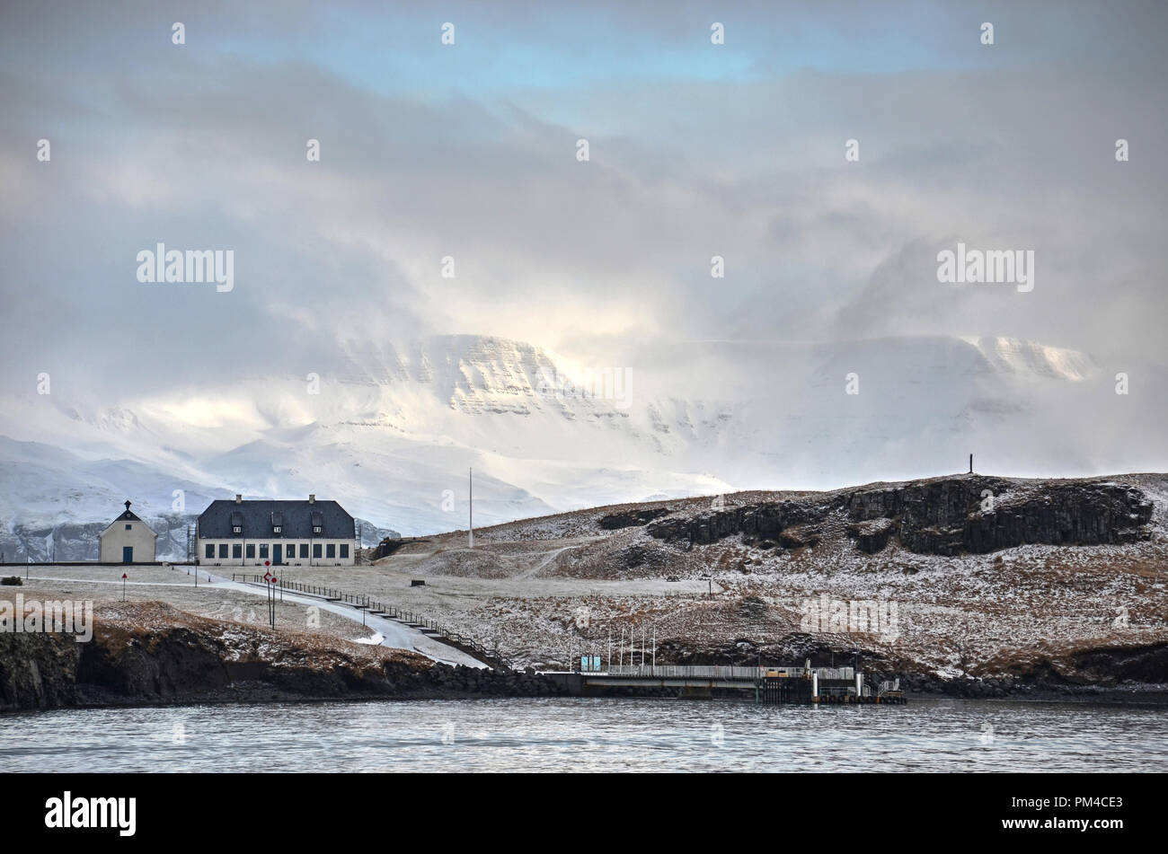 Low clouds partially obscure the snow-covered mountains behind Videy ...