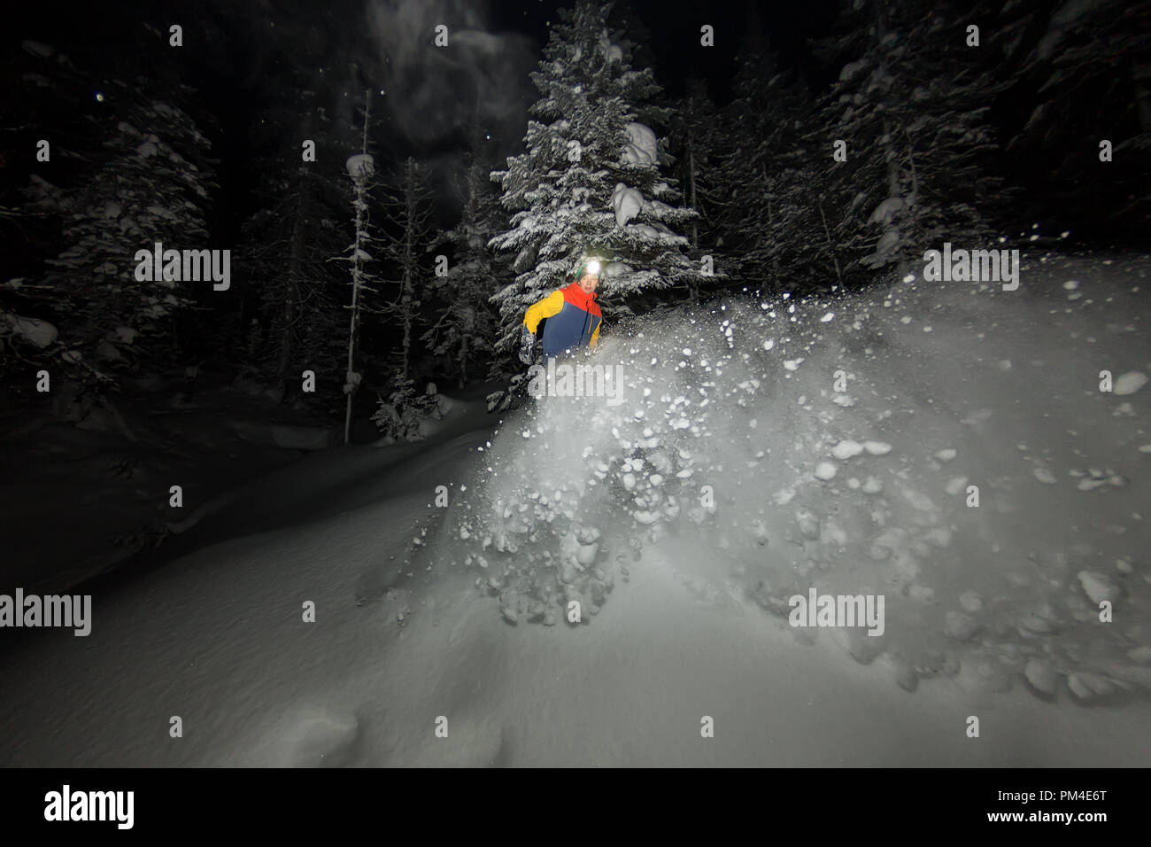 freerider snowboarder jumping at night with a springboard in the forest ...