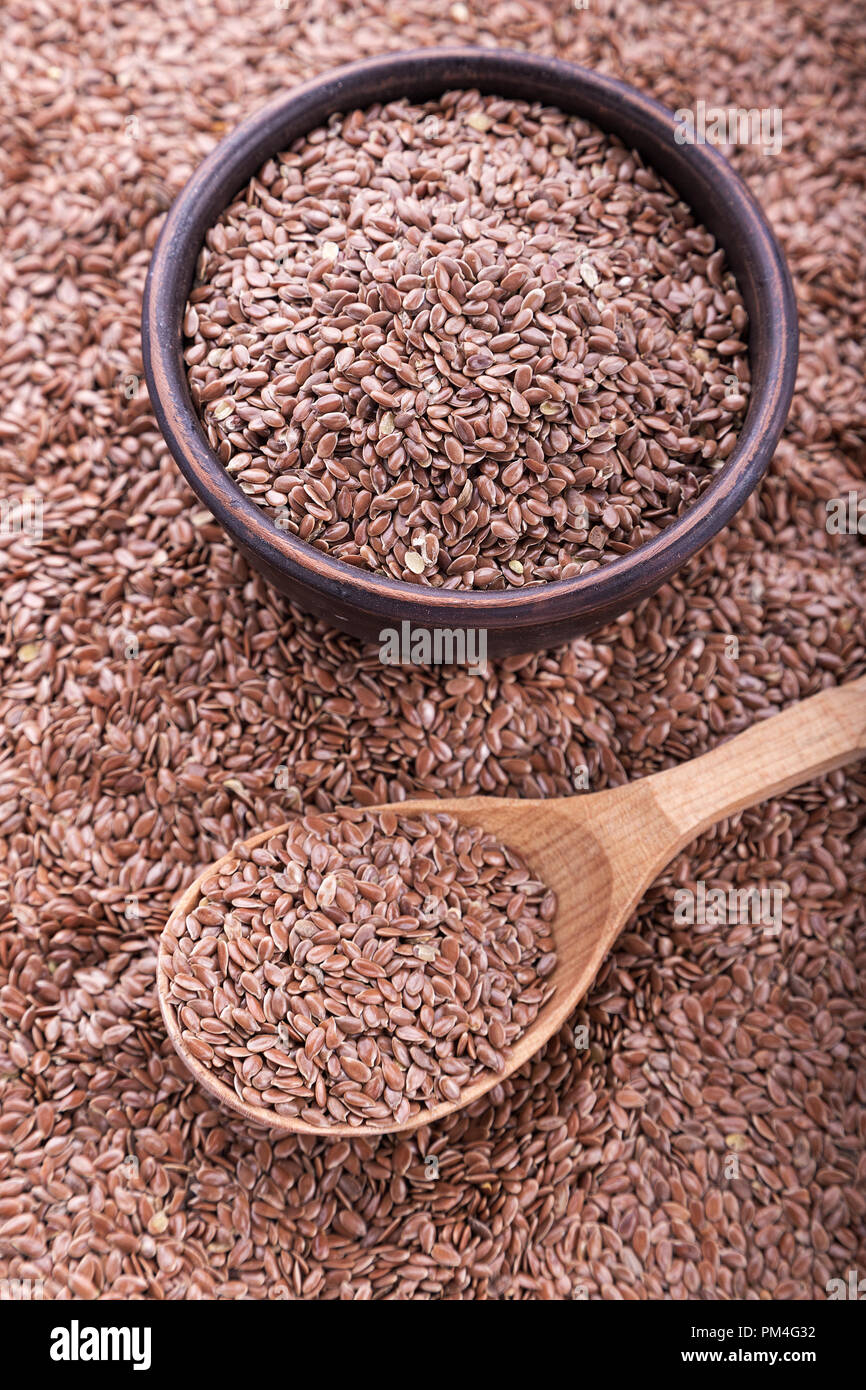 Flax seeds are scattered a solid background in a pile of seeds wooden spoon and plate with flax ...