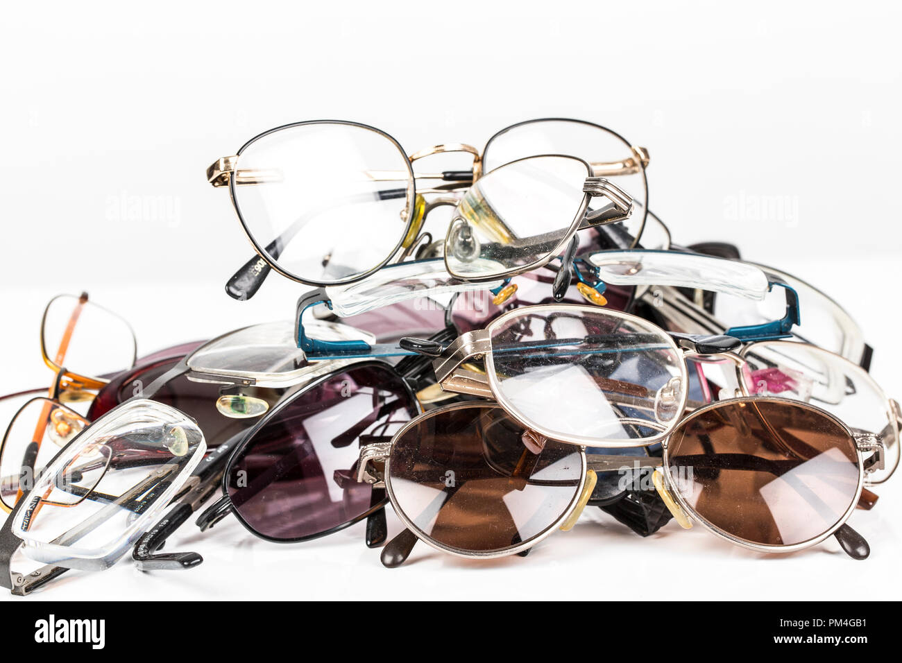 Old used eye reading glasses speclacles stacked in a pile on a white ...