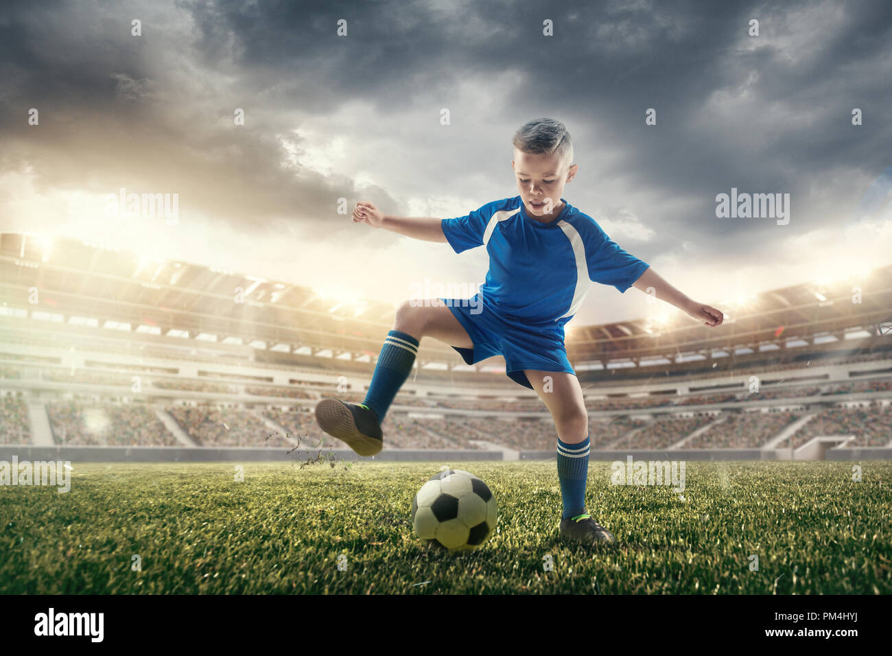 Young boy with soccer ball doing flying kick at stadium. football ...
