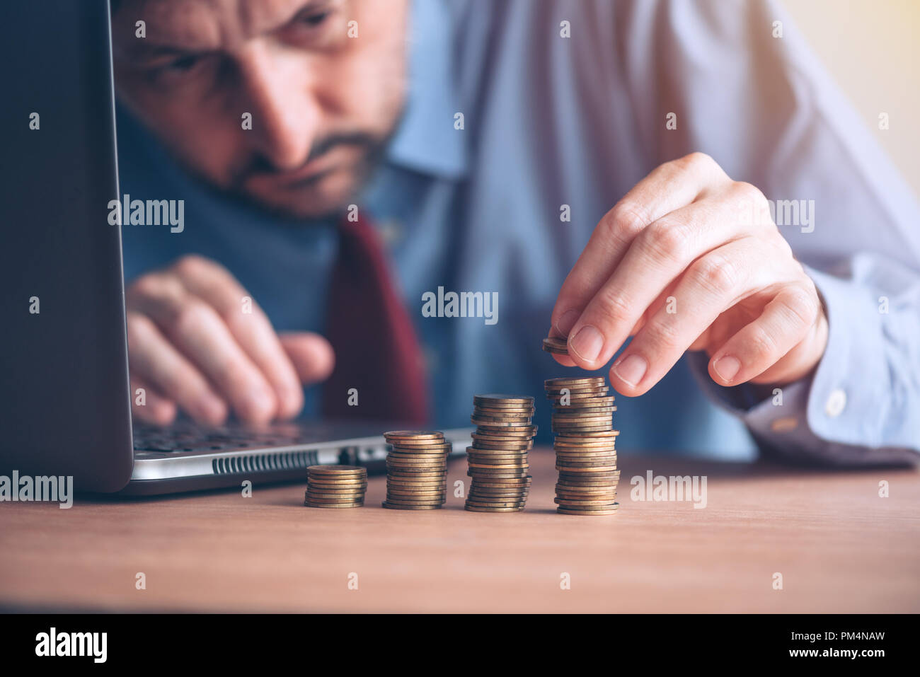 Coin stacker, businessman with stacked money in the office doing ...