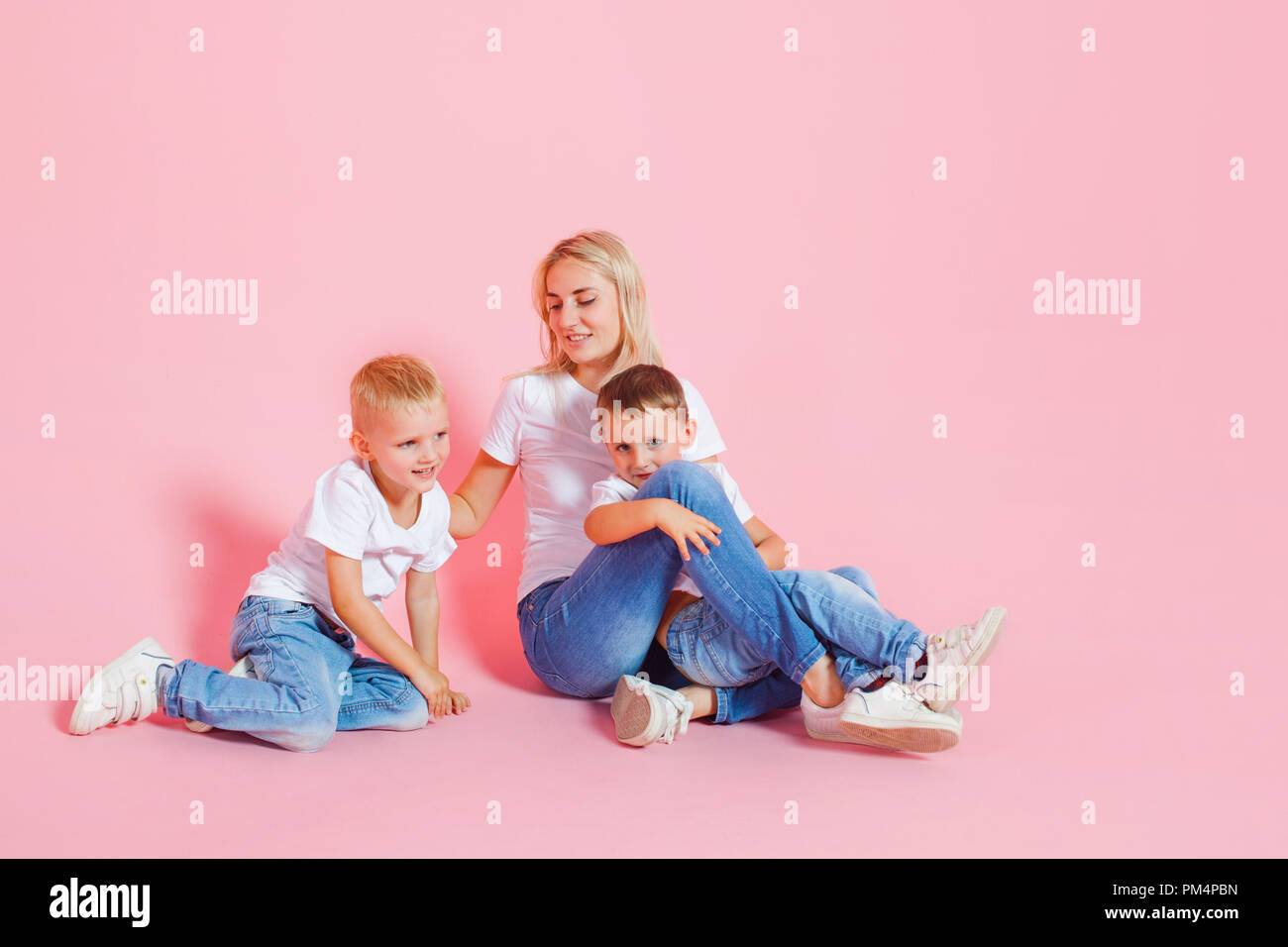 Beautiful blonde mom with two happy sons. Young woman and two baby boys ...