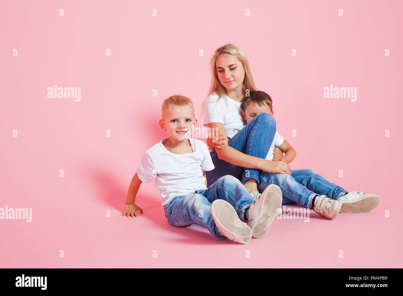 happy mom with two happy sons. Young woman and two baby boys, pink ...