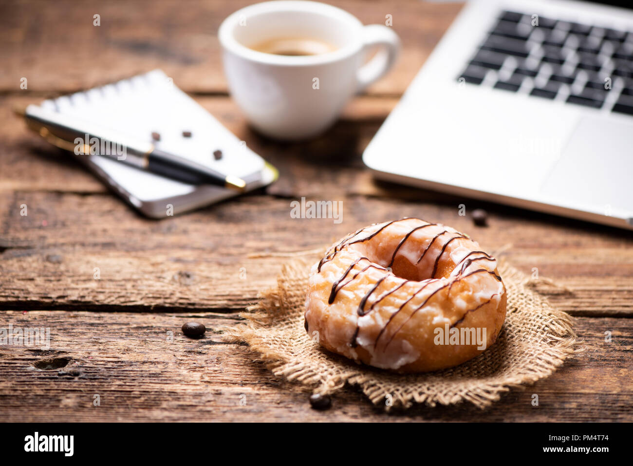 Coffee break. Doughnut on desk with a notebook pad and coffee Stock ...