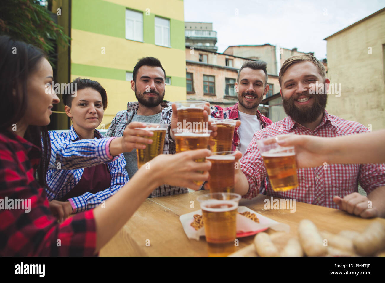 The group of friends enjoying and drinking beer at outdoor bar or pub ...