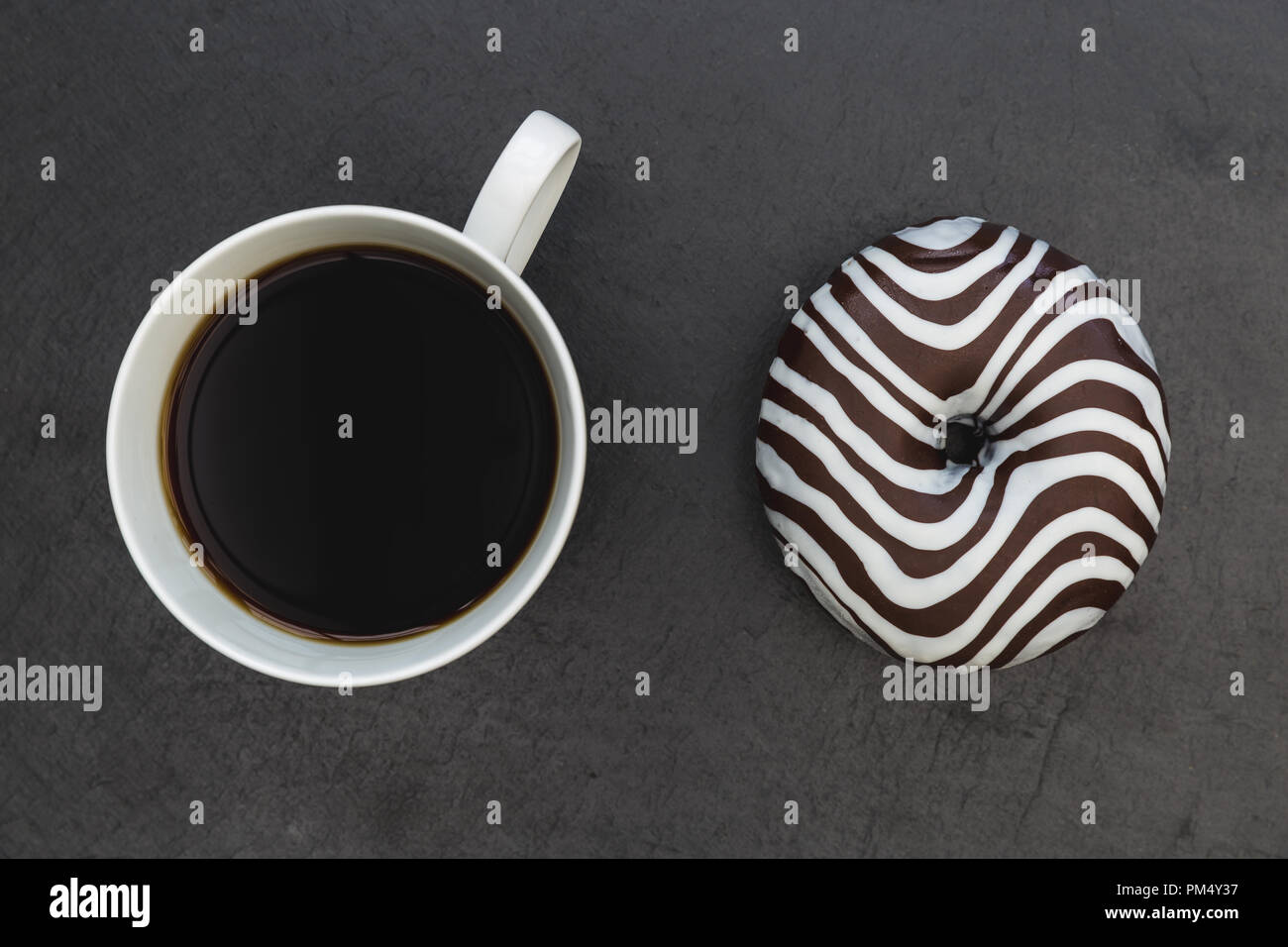 Striped donut and coffee cup on dark background Stock Photo - Alamy