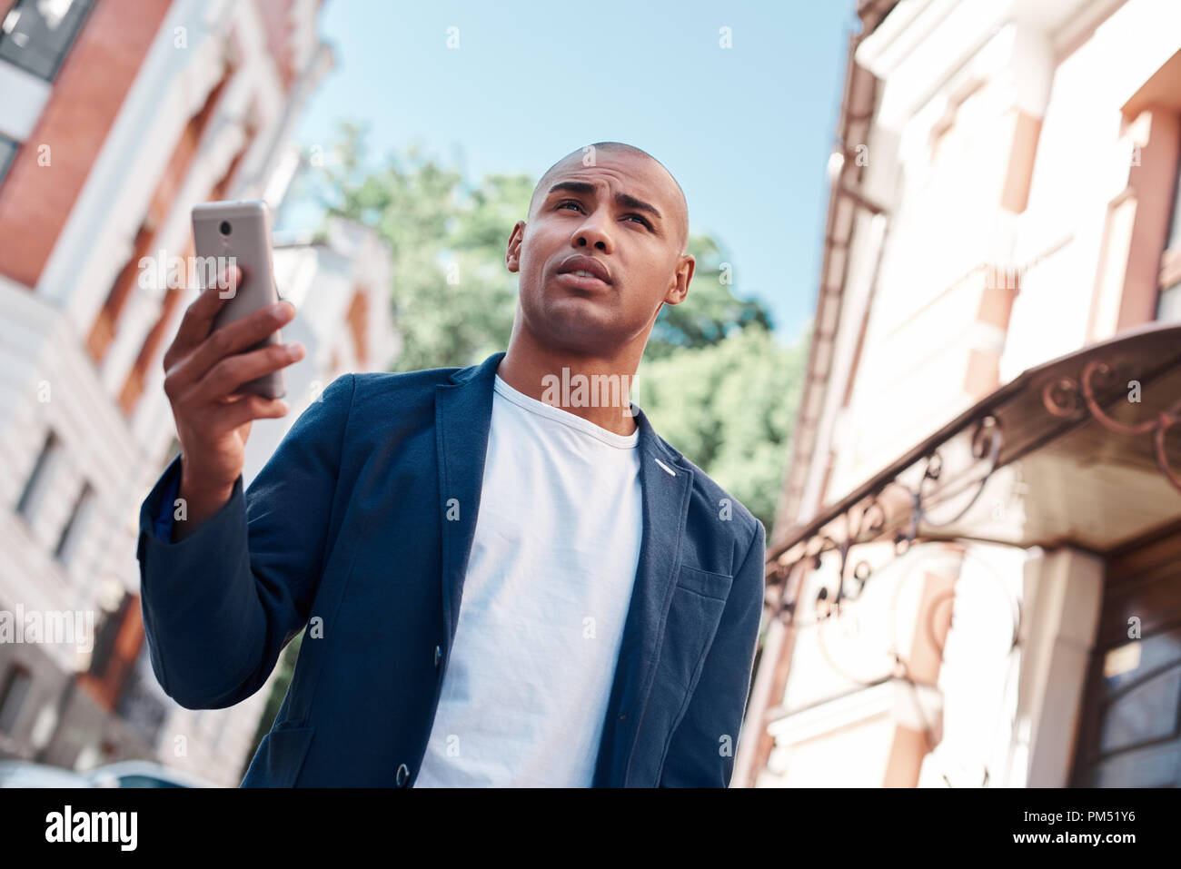 Finding location. Young man walking on the city street holding ...