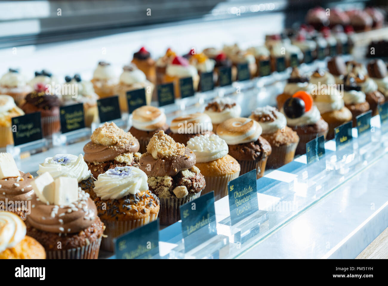 Various muffins and cupcakes for sale in a bakery display case Stock ...