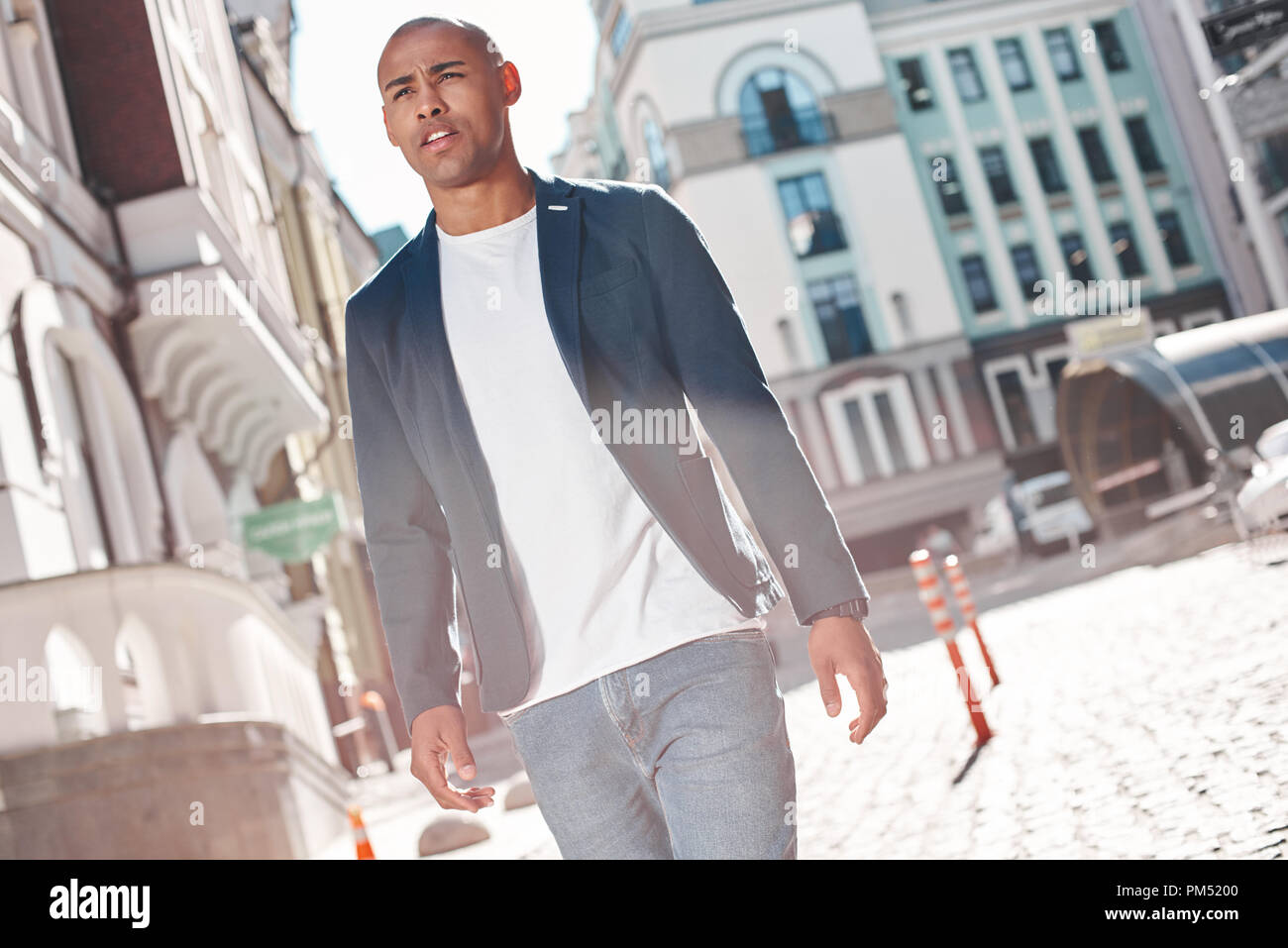 City walk. Young man walking on the street pensive Stock Photo - Alamy