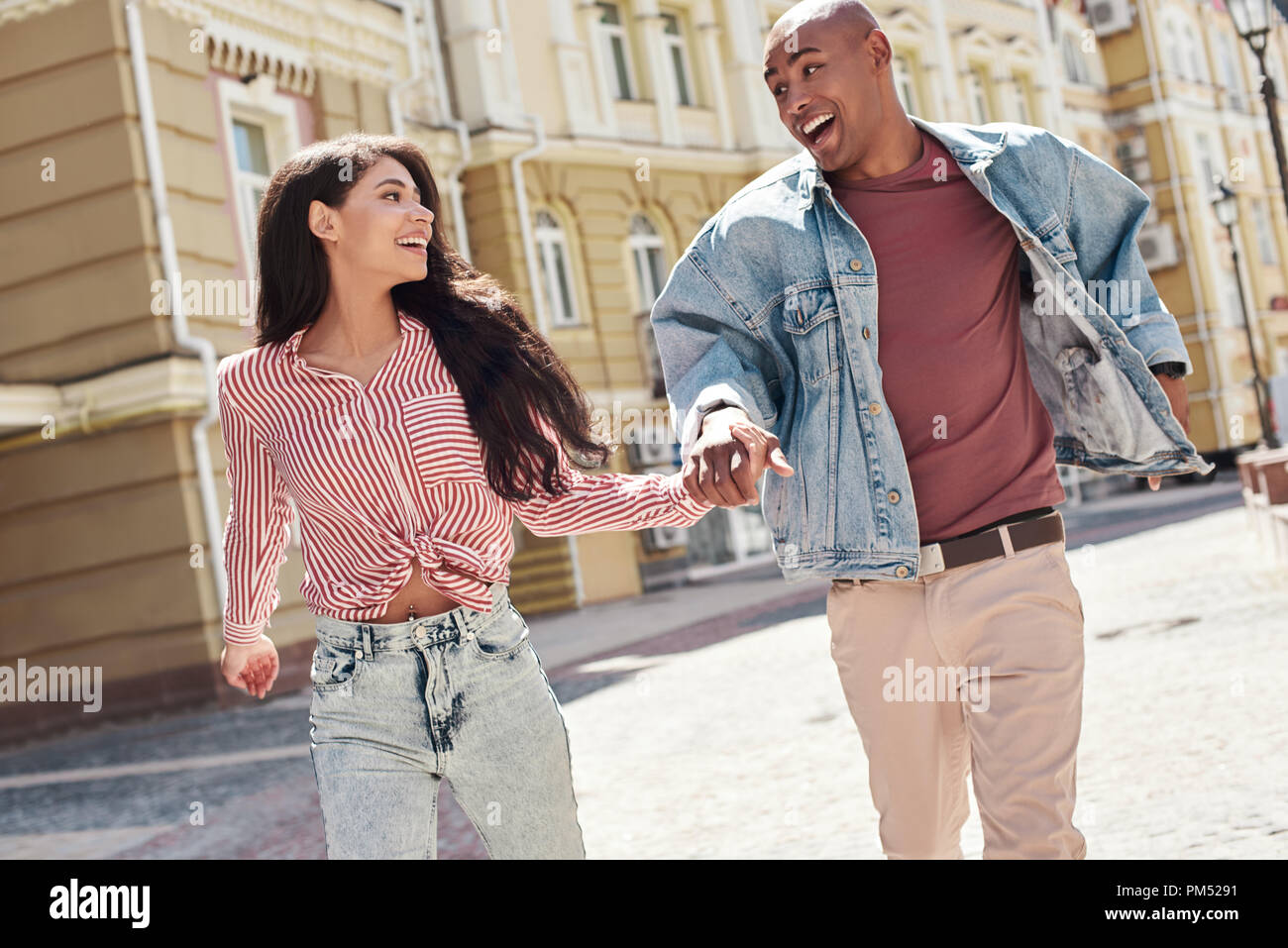 Romantic Relationship. Young diverse couple running on the city street ...