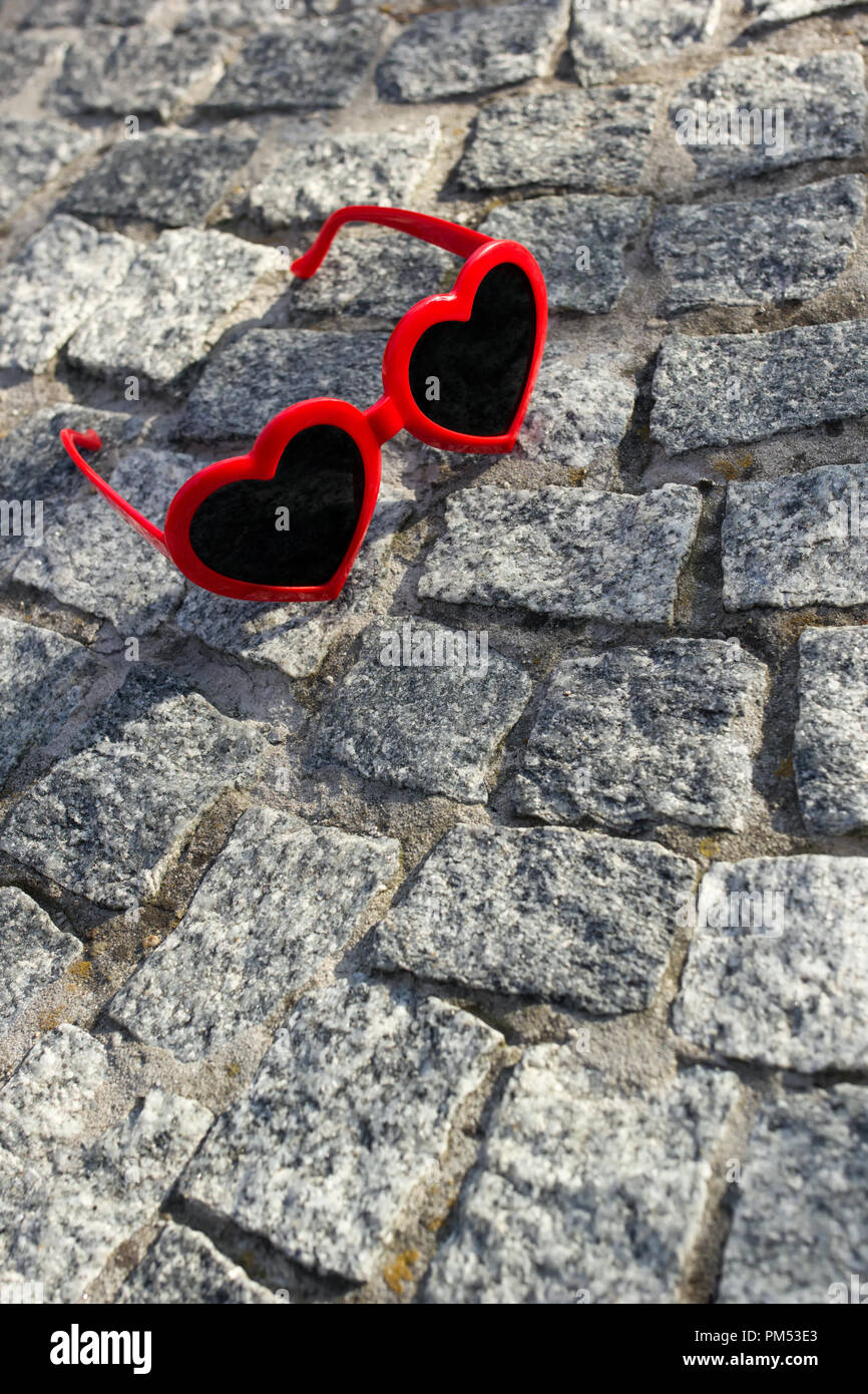 Red, heart shaped sunglasses on a floor on cobblestone street Stock Photo - Alamy