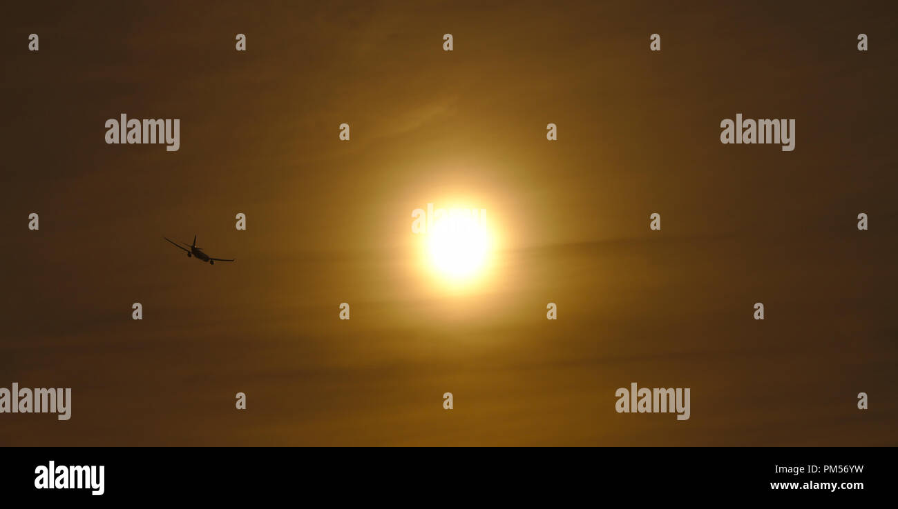 Plane flying away into the evening sun. Dark silhouette of the aircraft ...