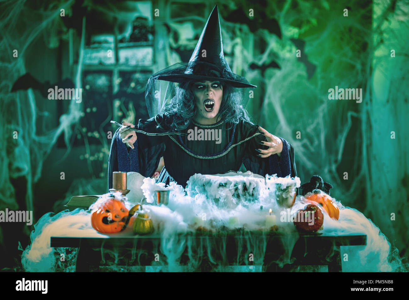 Witch with awfully face and hat on her head in creepy surroundings full ...