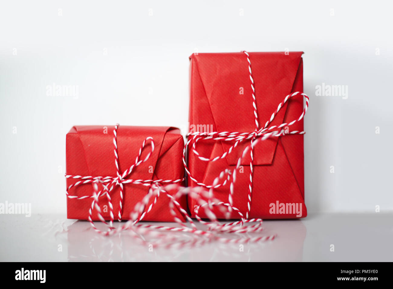 Christmas gift boxes wrapped in red paper and bow of dtriped rope on ...