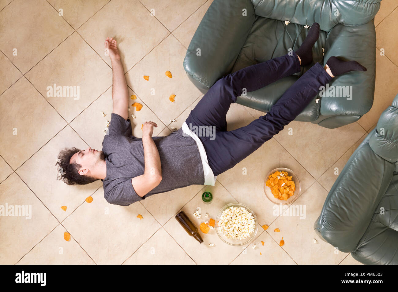 Young man after heavy partying at home. A lot of beer and junk food ...