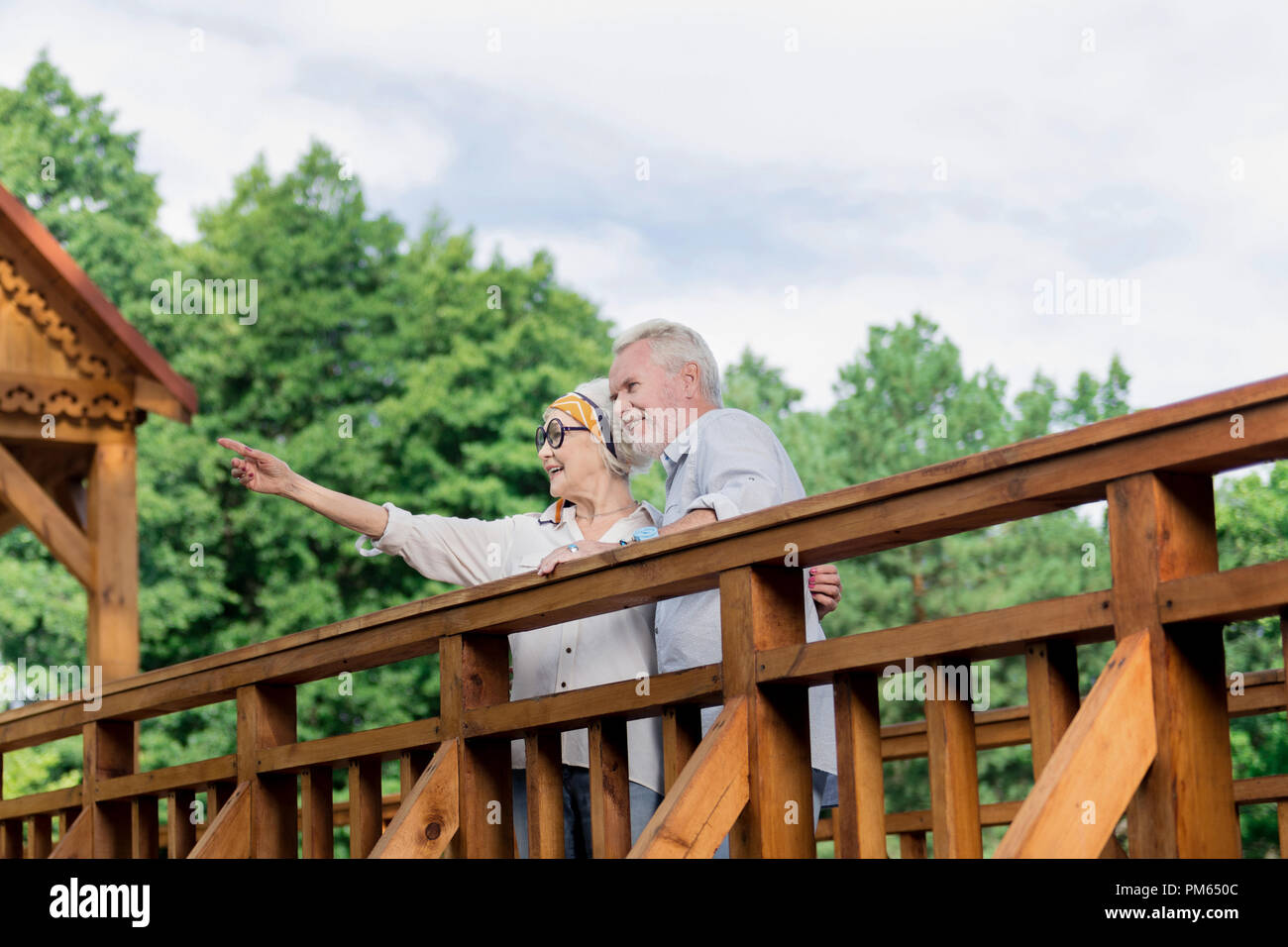 Positive aged woman pointing to the distance while standing with her ...
