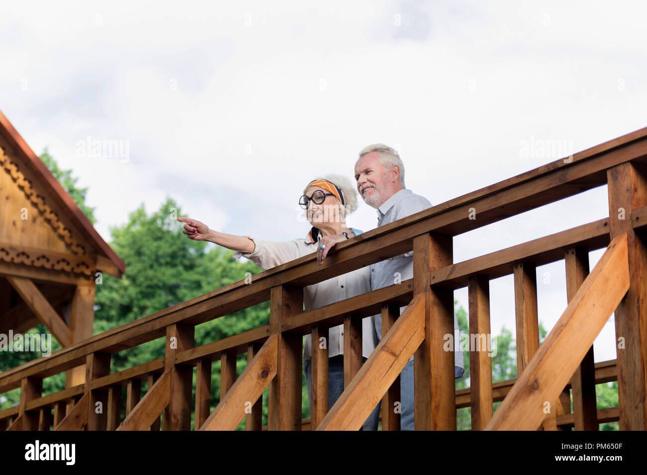 Cheerful elderly woman pointing into the distance and smiling to her ...