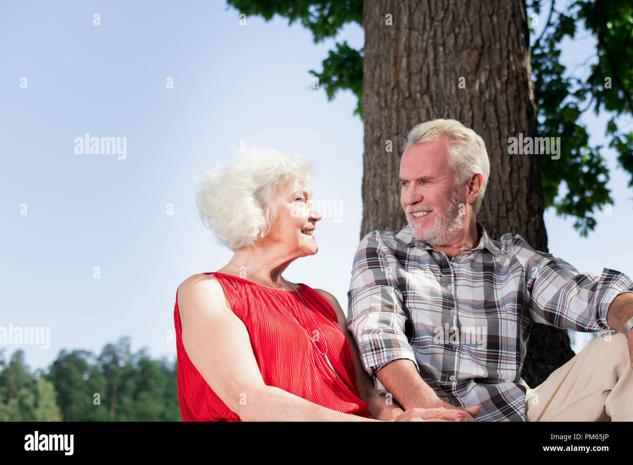 Cheerful pensioners smiling to each other while having romantic date ...