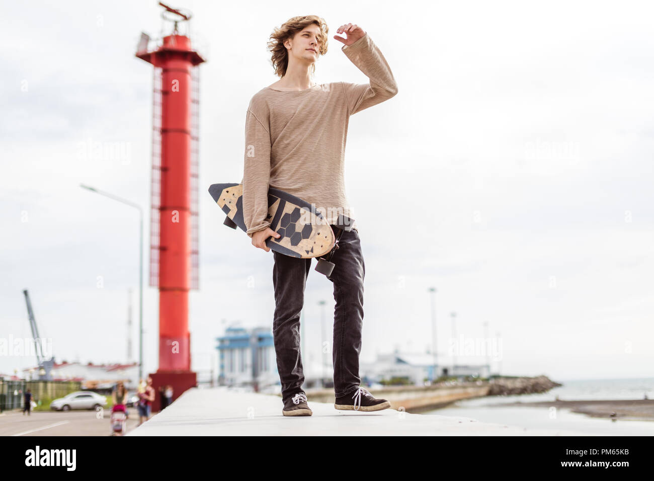 Stylish man stands on street and hold long board in hands Stock Photo ...