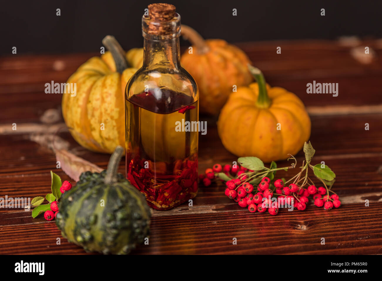 homemade olive oil with chilli pepper surrounded by pumpkins, leaves ...