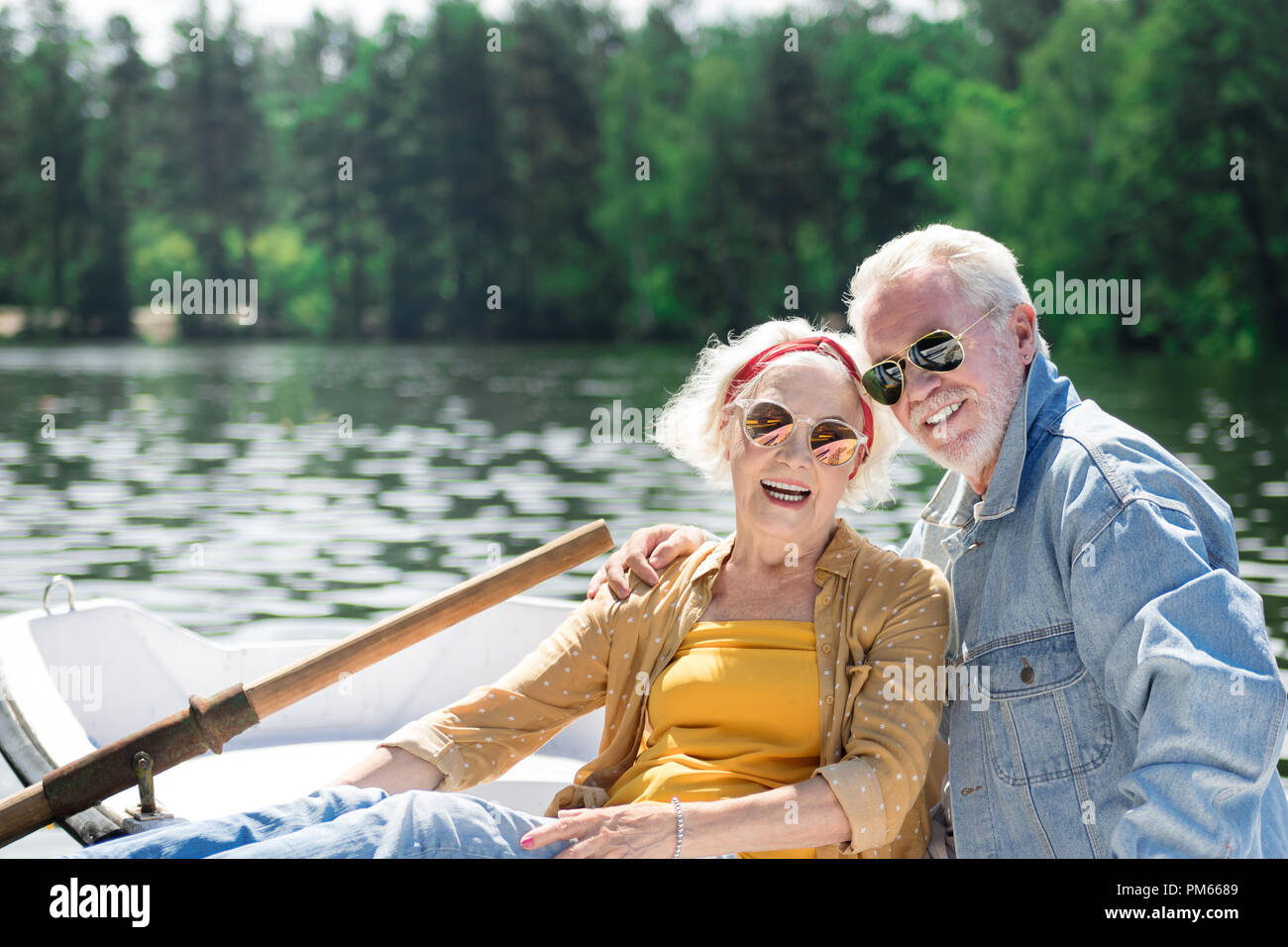 Smiling in boat. Positive active couple of pensioners smiling and ...