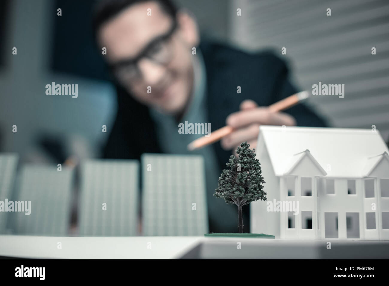 View of model of a house with man on background Stock Photo - Alamy