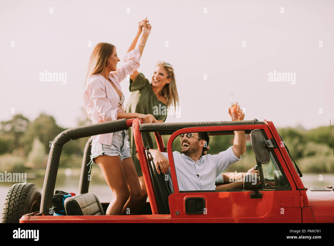 Happy friends having fun in convertible car at vacation by river Stock ...