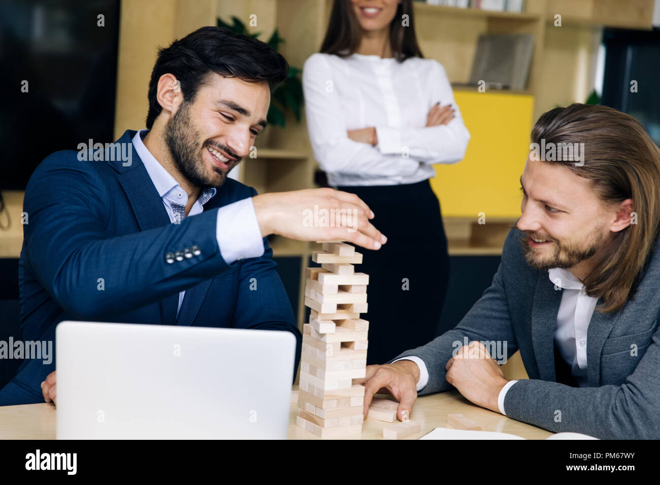 Team of young business people build a wooden construction in the office ...
