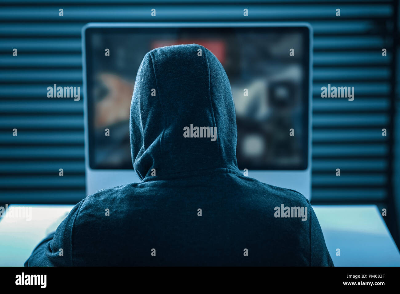 View of man in hood sitting in front of computer Stock Photo - Alamy