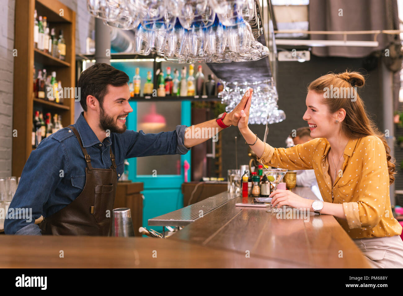 Happy young barman smiling and giving five to the visitor Stock Photo ...