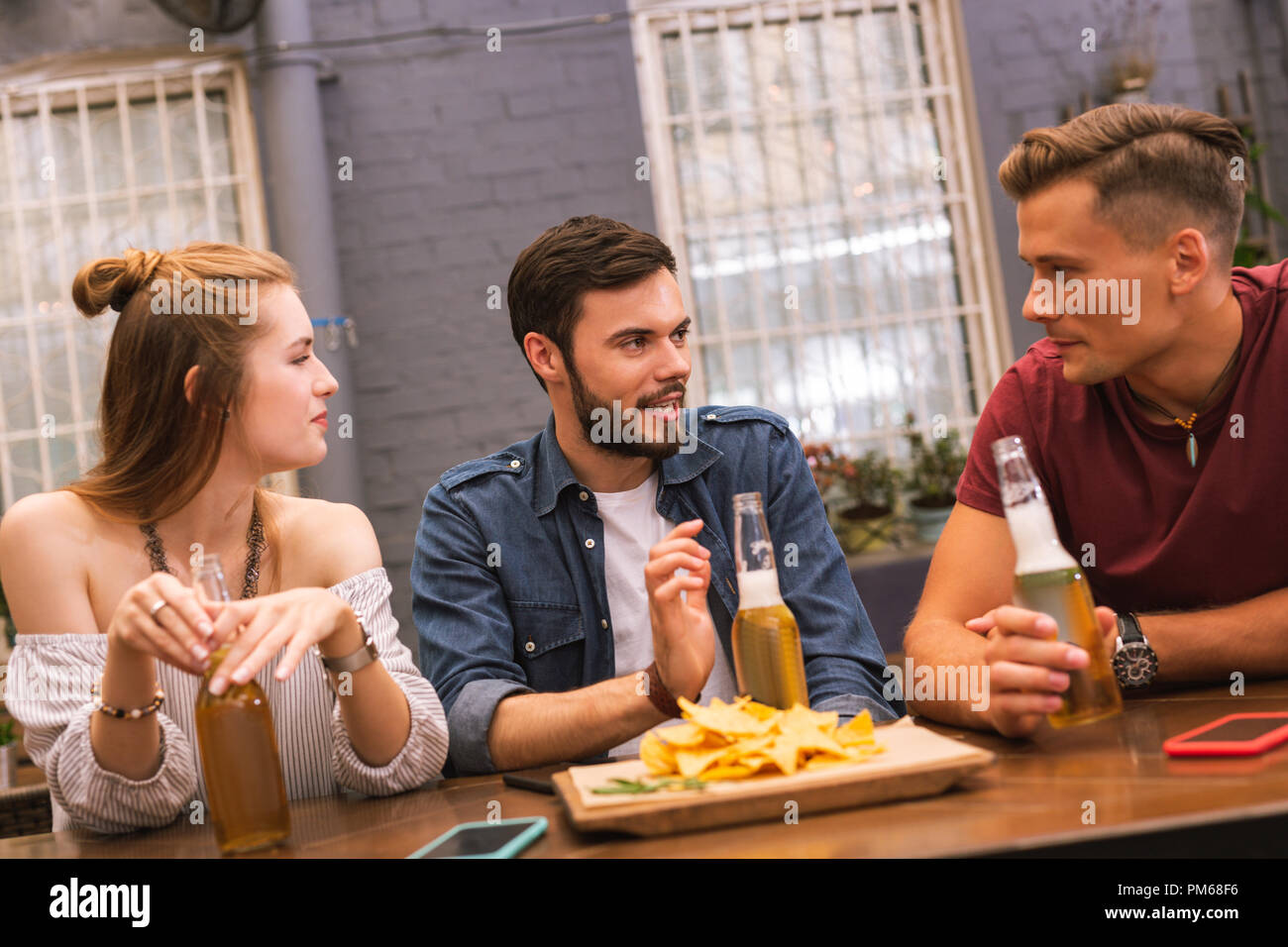 Two people looking at their friend and smiling while talking Stock ...