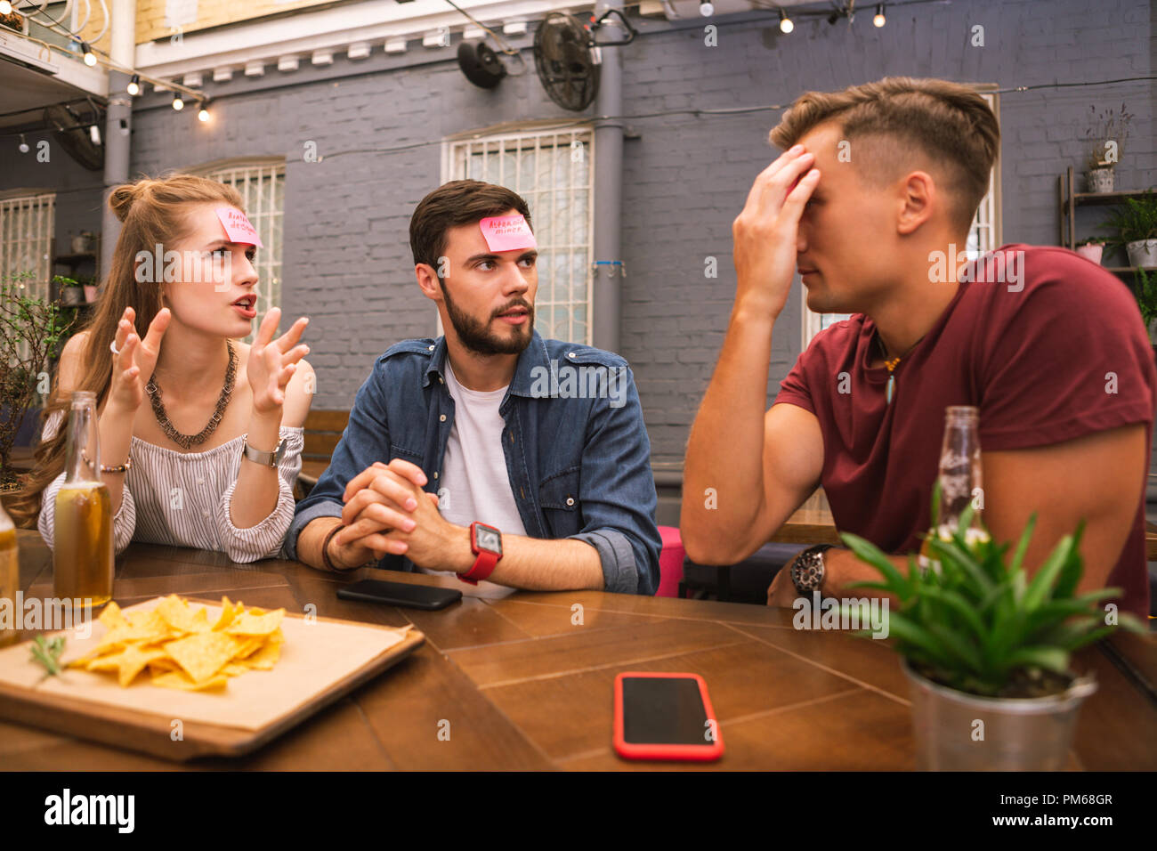 Curious friends using gestures while explaining words in the game Stock ...