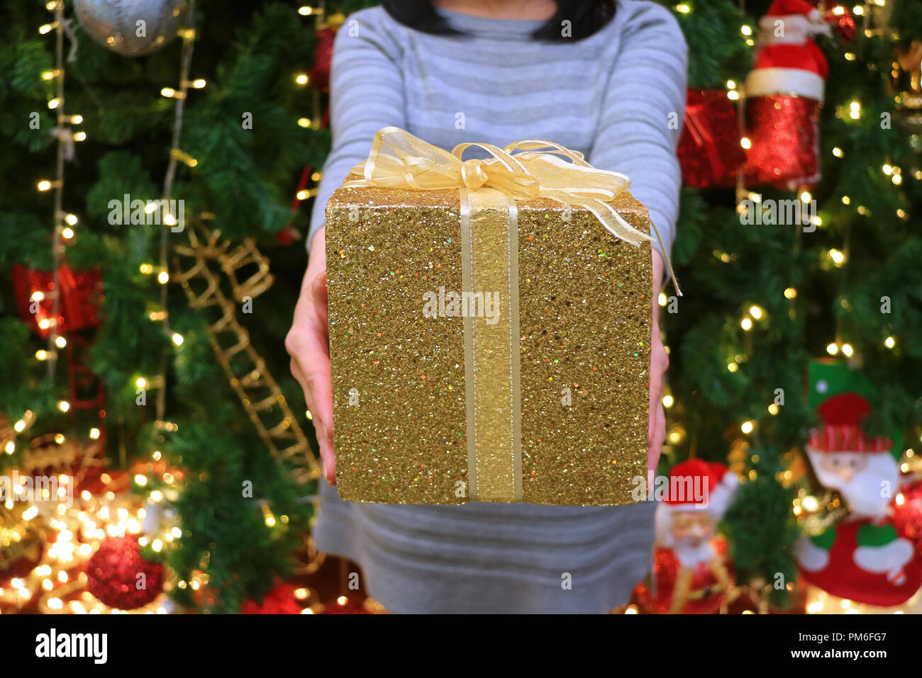 Female handing a gold glitter square shape gift box wrapped with gold ...