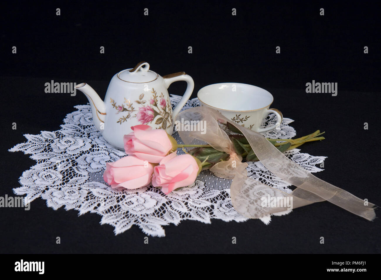 Vintage pink rose tea set isolated on black background and resting on ...