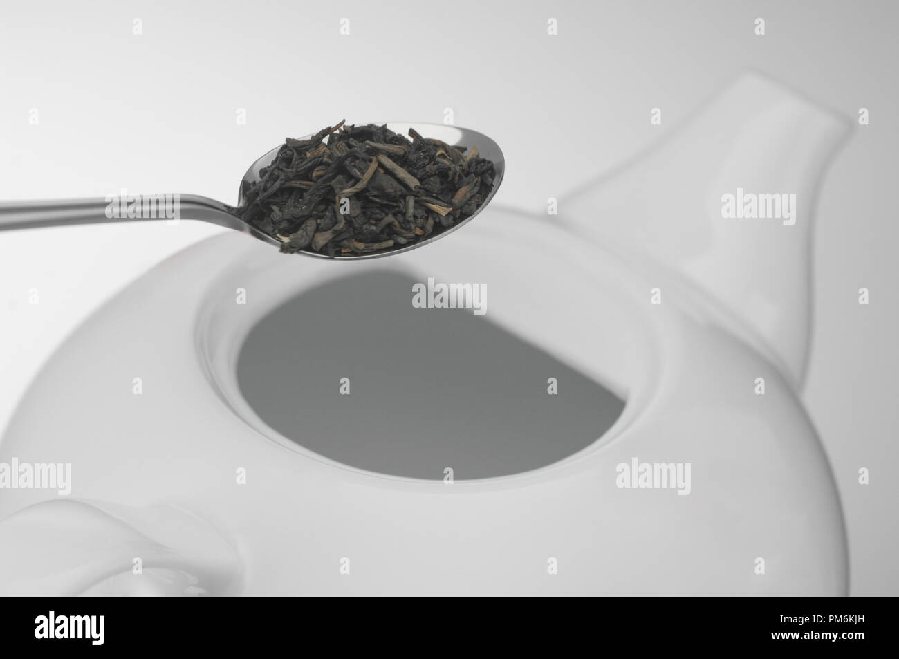 spoon with tea leaves and a white ceramic teapot, macro shooting Stock ...