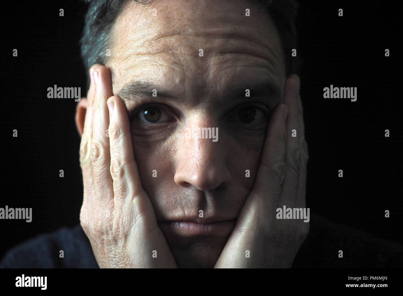 Portrait of man on black background, stressed, hands on face Stock ...