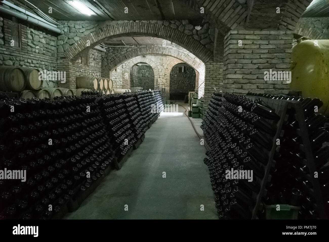 Ancient wine cellar with oak barrels and shelves with bottles of Stock ...
