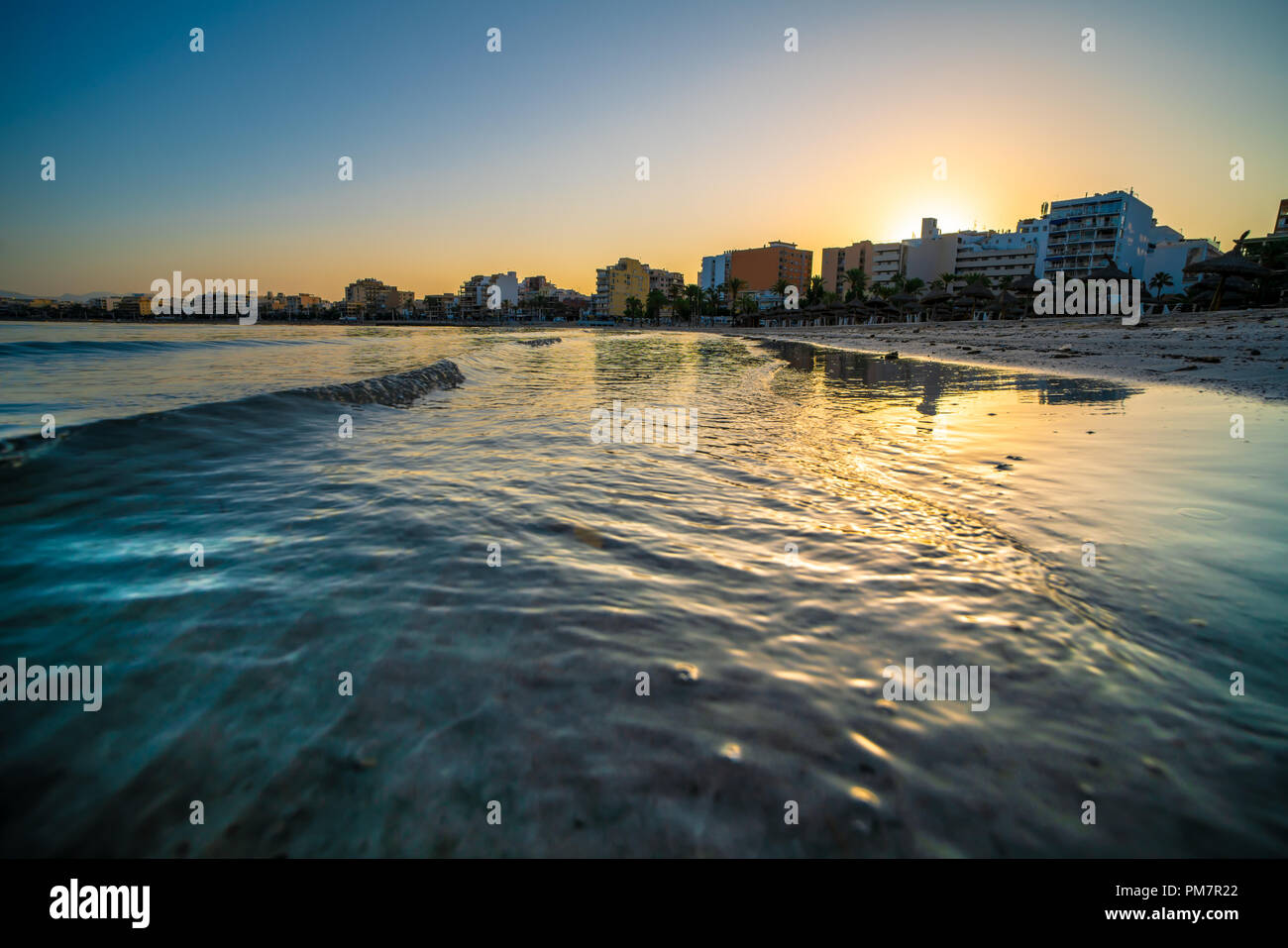 Wavy curves of sea is covered in golden sunset light. Sea at sunset ...