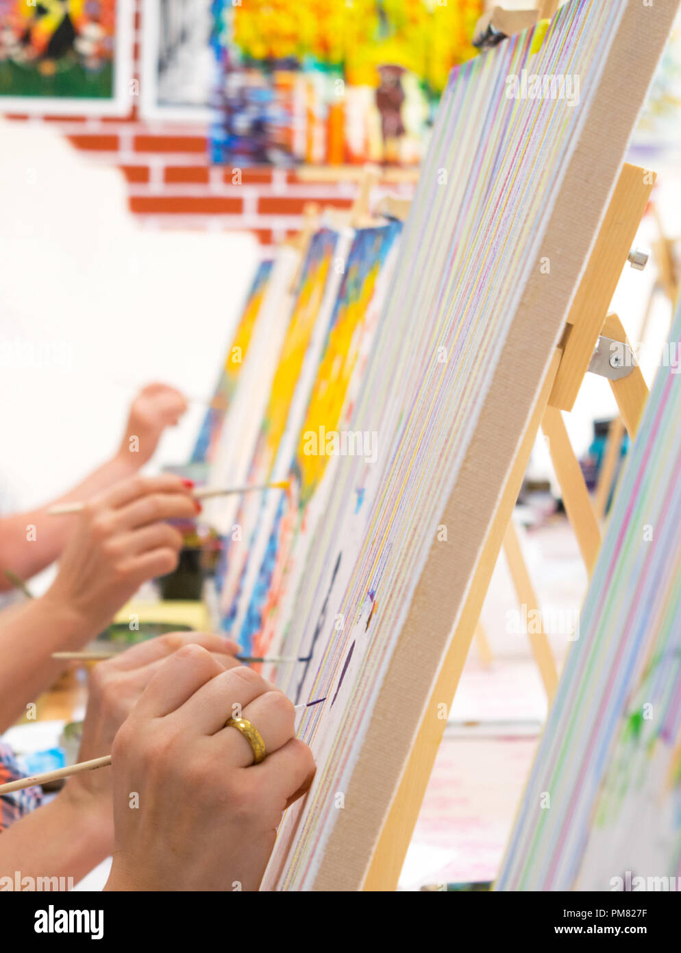 Many women of different ages drawing on canvases with brushes during ...